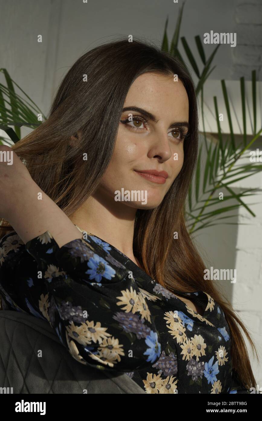 Proud Young girl wearing floral dress enjoying sun light while smiling ...