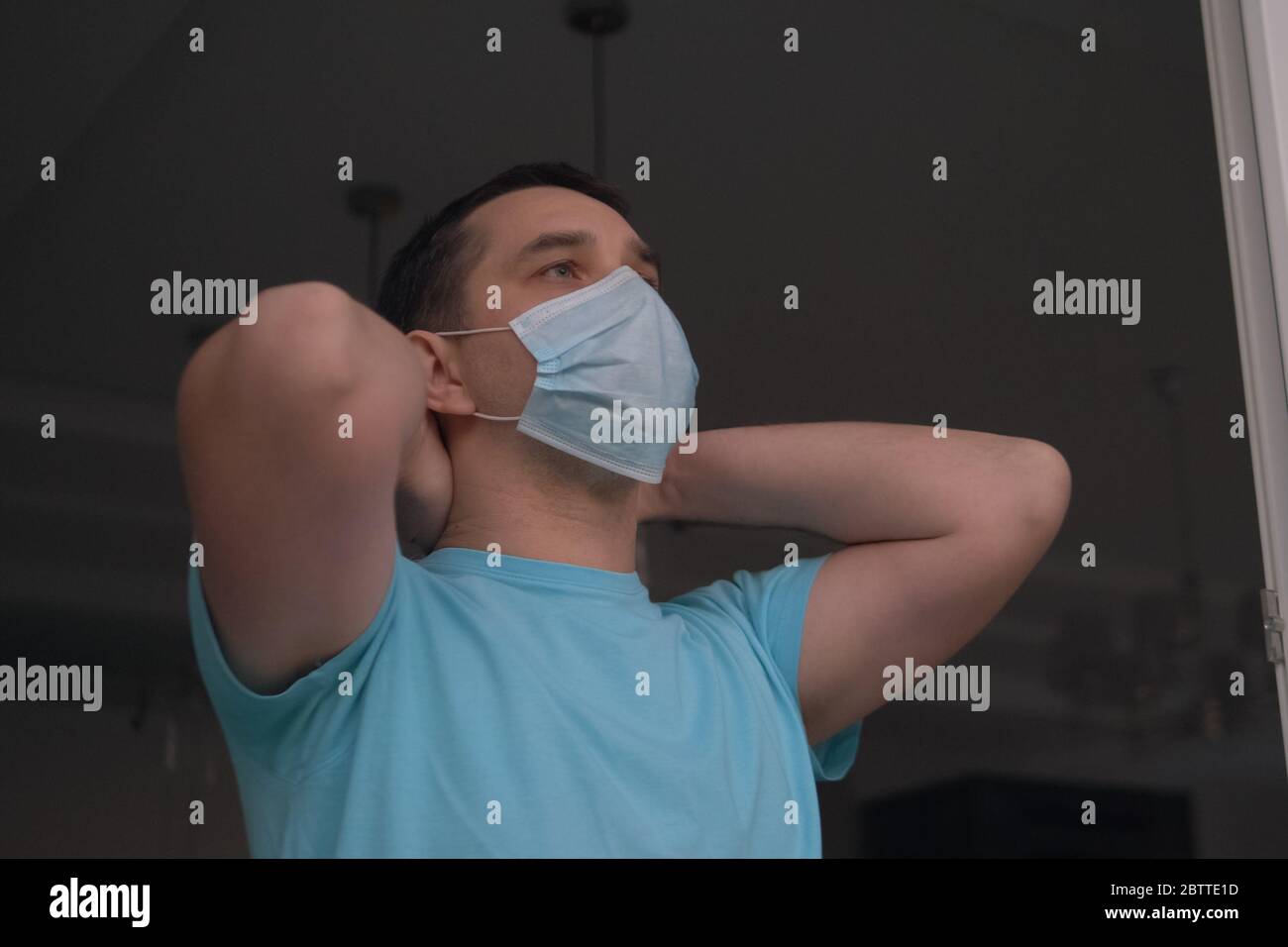 Sad man in a medical mask look at the window. 4K Stock Photo - Alamy