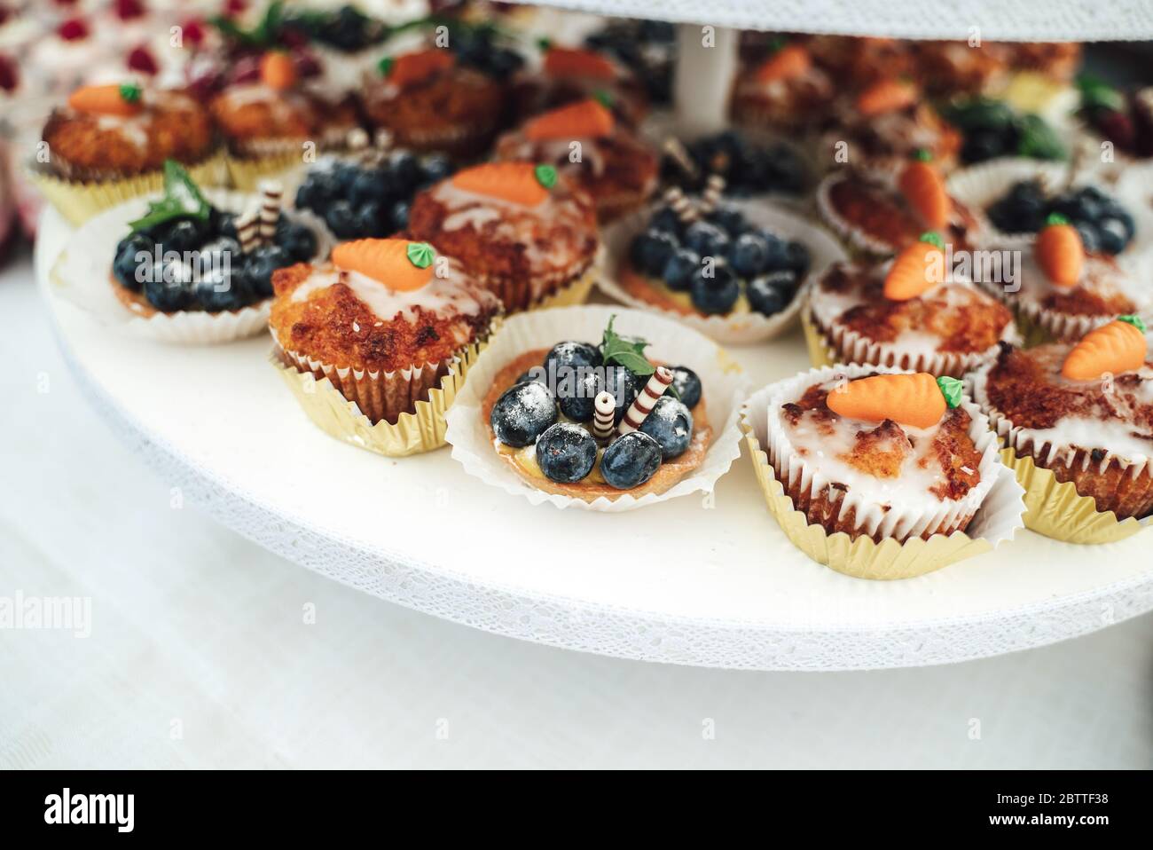 Delicious miniature cakes in buffet trays. Fruit decorated cupcakes ...