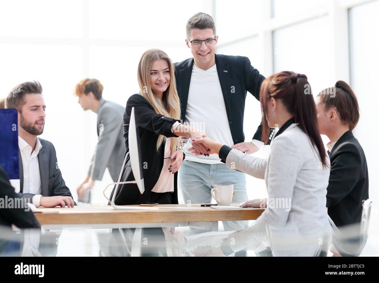two young women shaking hands near an office Desk Stock Photo - Alamy