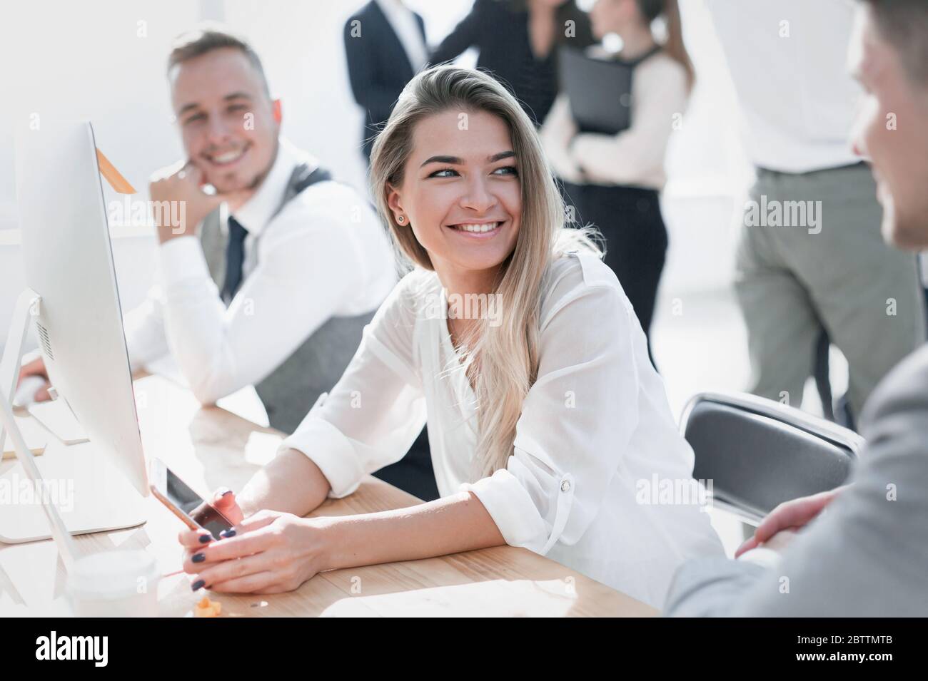 close up. young employees sitting at the office Desk Stock Photo - Alamy