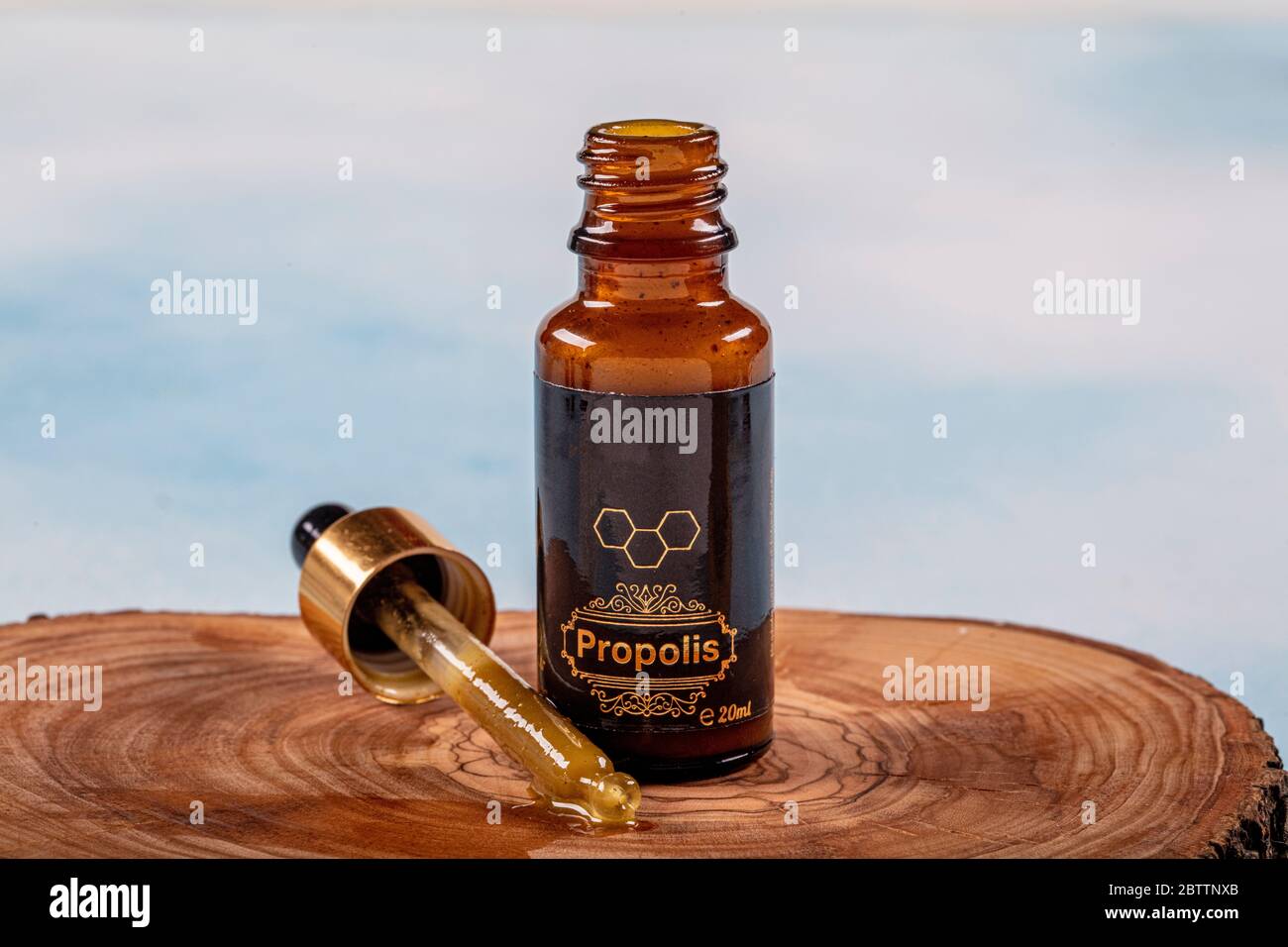 Propolis Drop Oil drop falling. A bottle of propolis on piece of wood ...