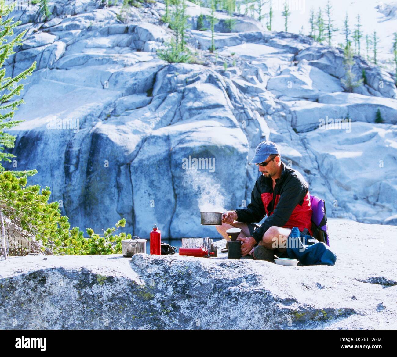 A man boiling water in the backcountry with a backpacking stove ...