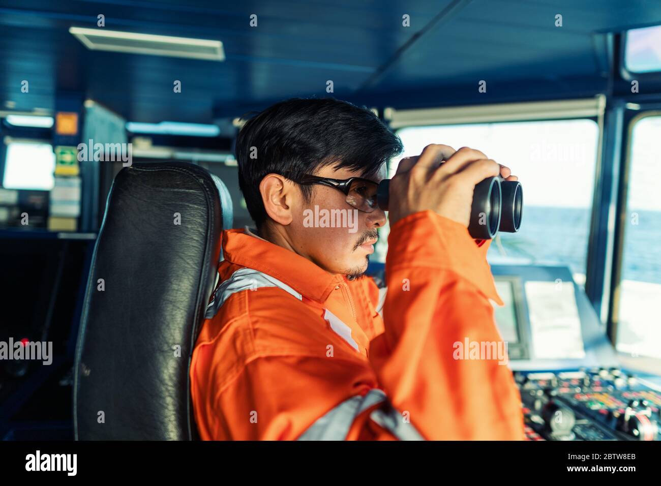Filipino deck Officer on bridge of vessel or ship looking through ...