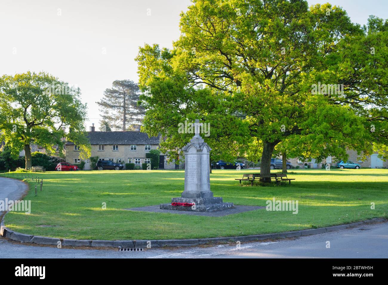 War memorial and oak trees on the village green in spring at sunrise ...