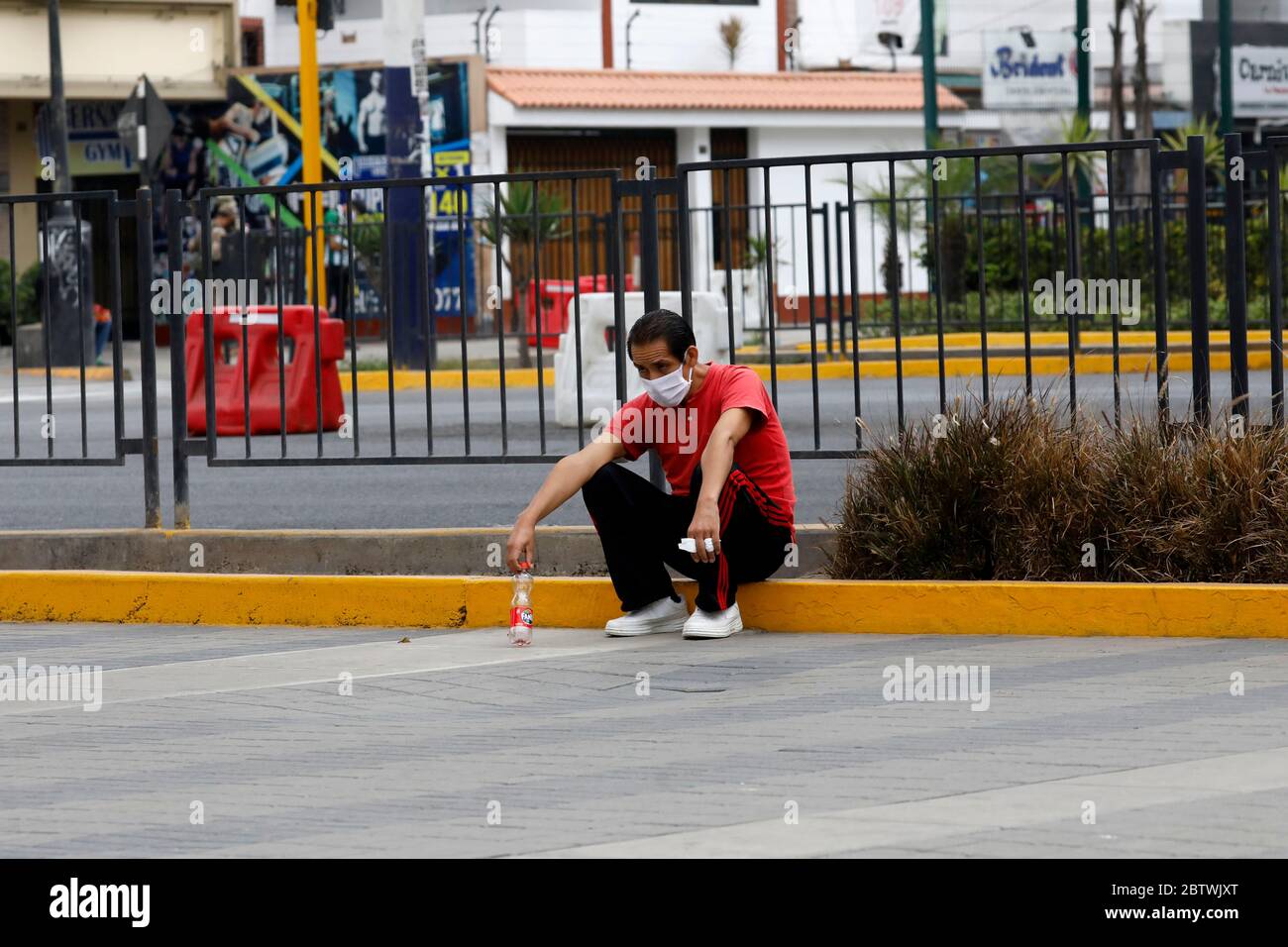 Lima, Peru. 27th May, 2020. A man wearing a mask sits at a street ...