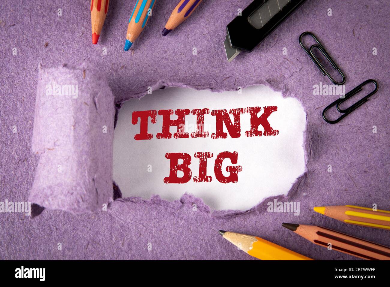 THINK BIG concept. Text under torn paper. Pencils and office supplies ...