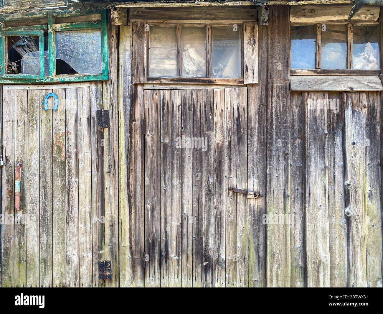 old weathered wooden barn wall. closed doors with padlocks and windows ...