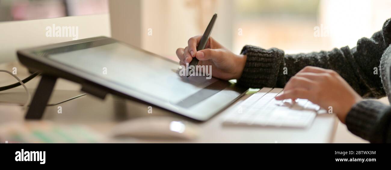 Side view of graphic designer working with drawing tablet and computer ...