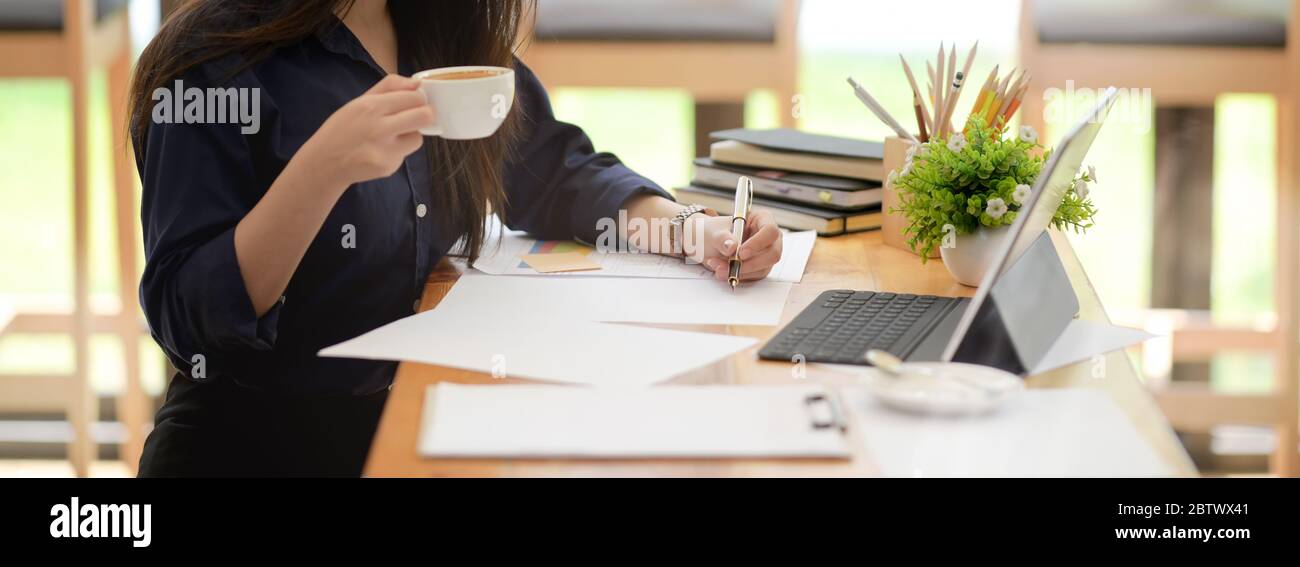 Side view of businesswoman working with document files and drinking ...