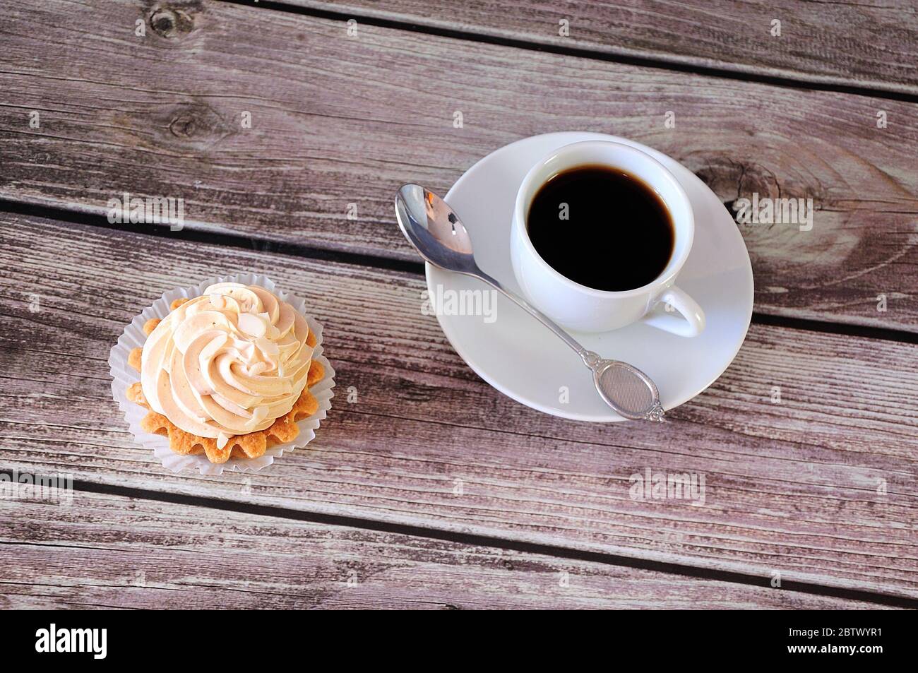 Shortbread cake with cream and a cup of strong black coffee on a wooden ...
