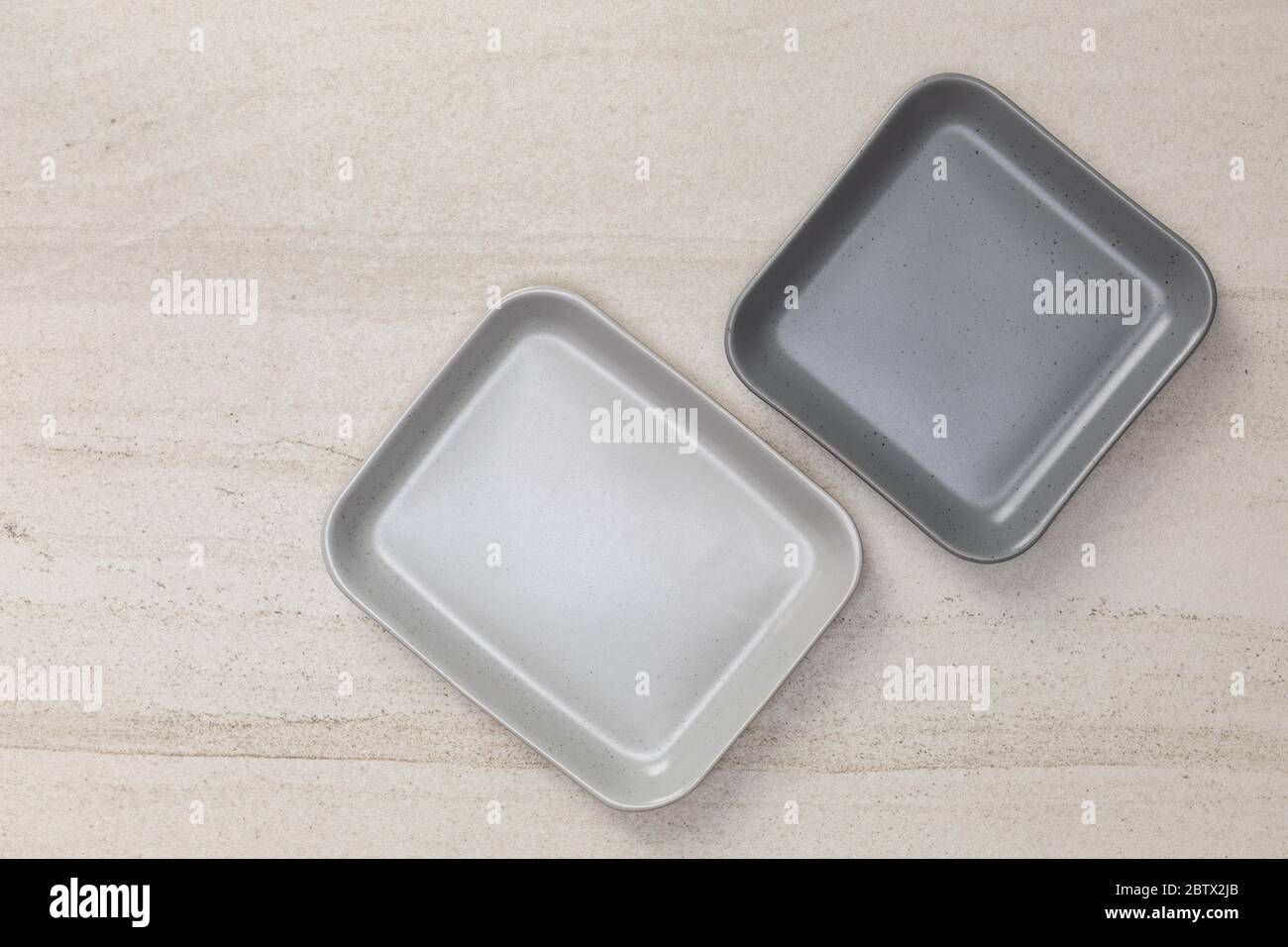 Group of empty blank ceramic square plates on white stone blackground ...