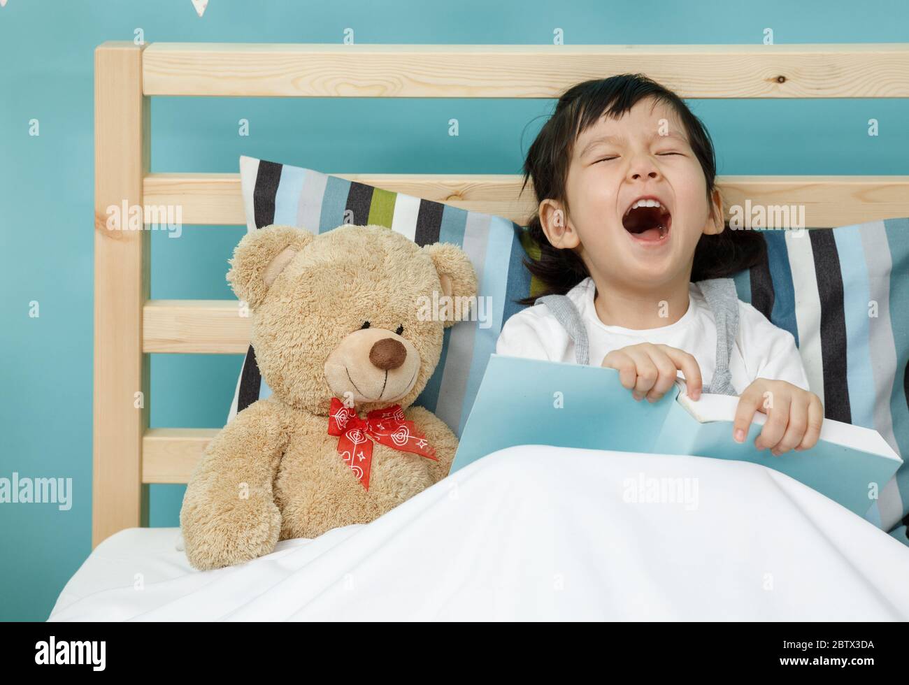 Child girl reading a book on the wooden bed in her bedroom, Happy asian ...