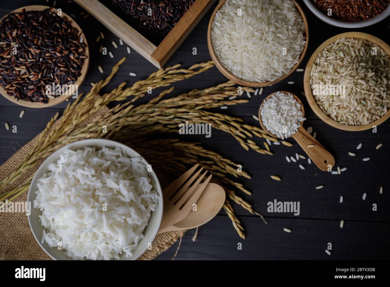 Cooked rice with dry rice and ears of jasmine rice on wooden table ...