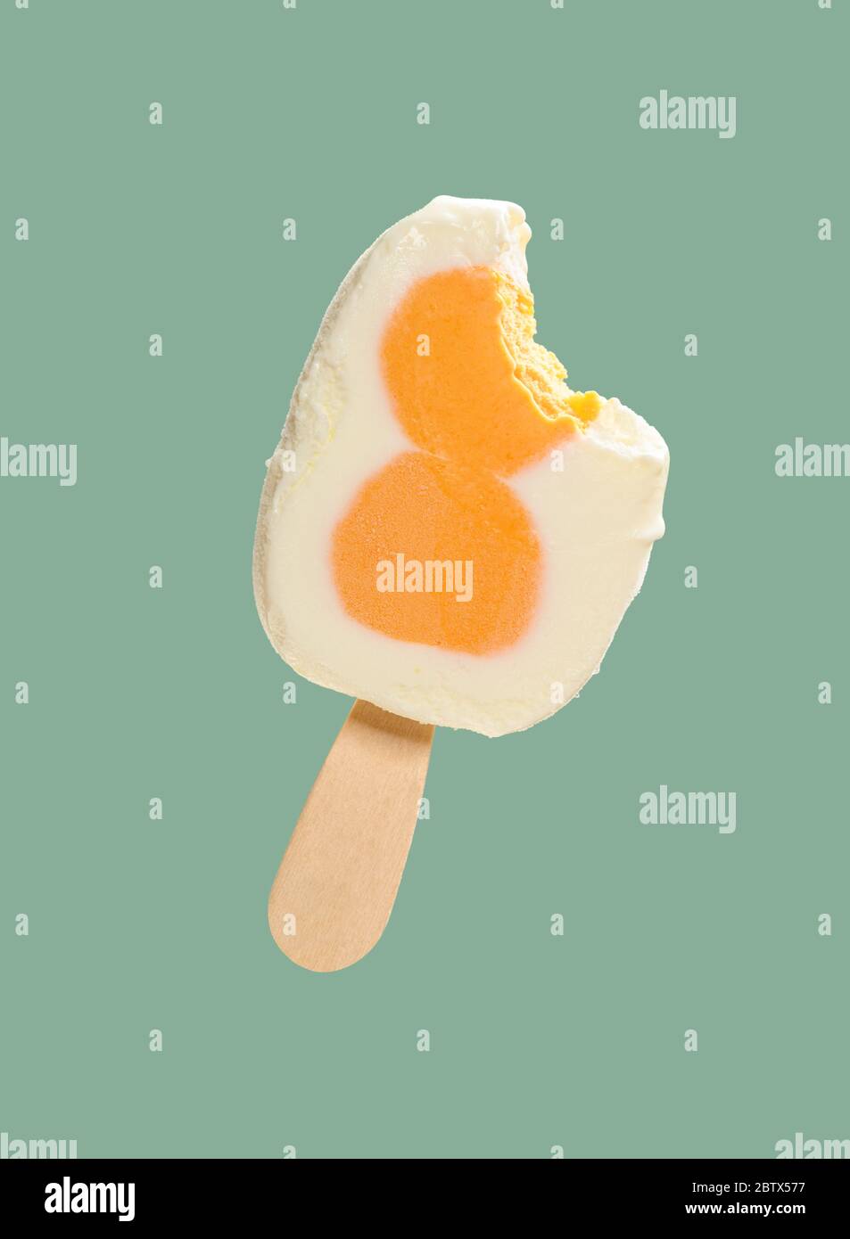 egg shape popsicle with a bite on green background Stock Photo - Alamy