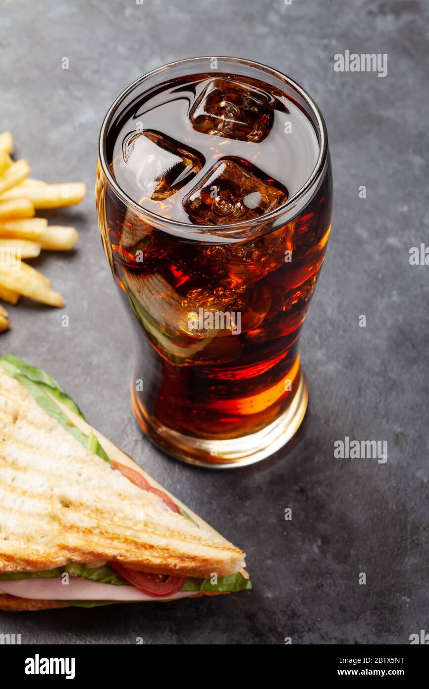 Glass of cola drink with ice, club sandwich and potato fries chips ...