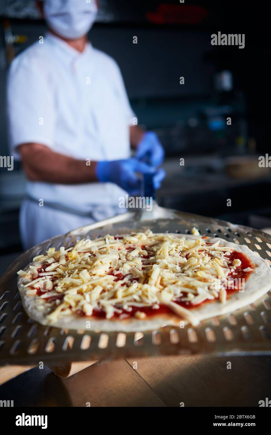 Skilled chef preparing traditional italian pizza in interior of modern ...