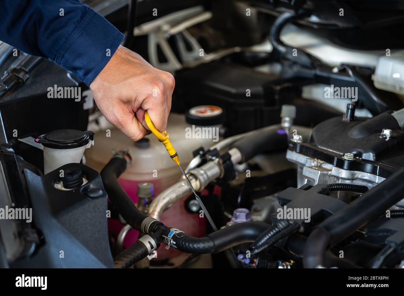 hand of technician checking the oil level on dipstick in a car engine ...