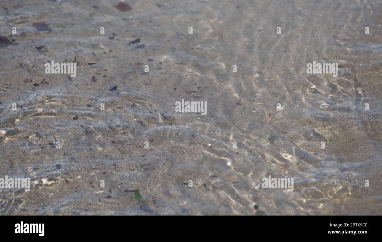 Sea water moving over a sandy beach on a warm sunny day Stock Photo - Alamy