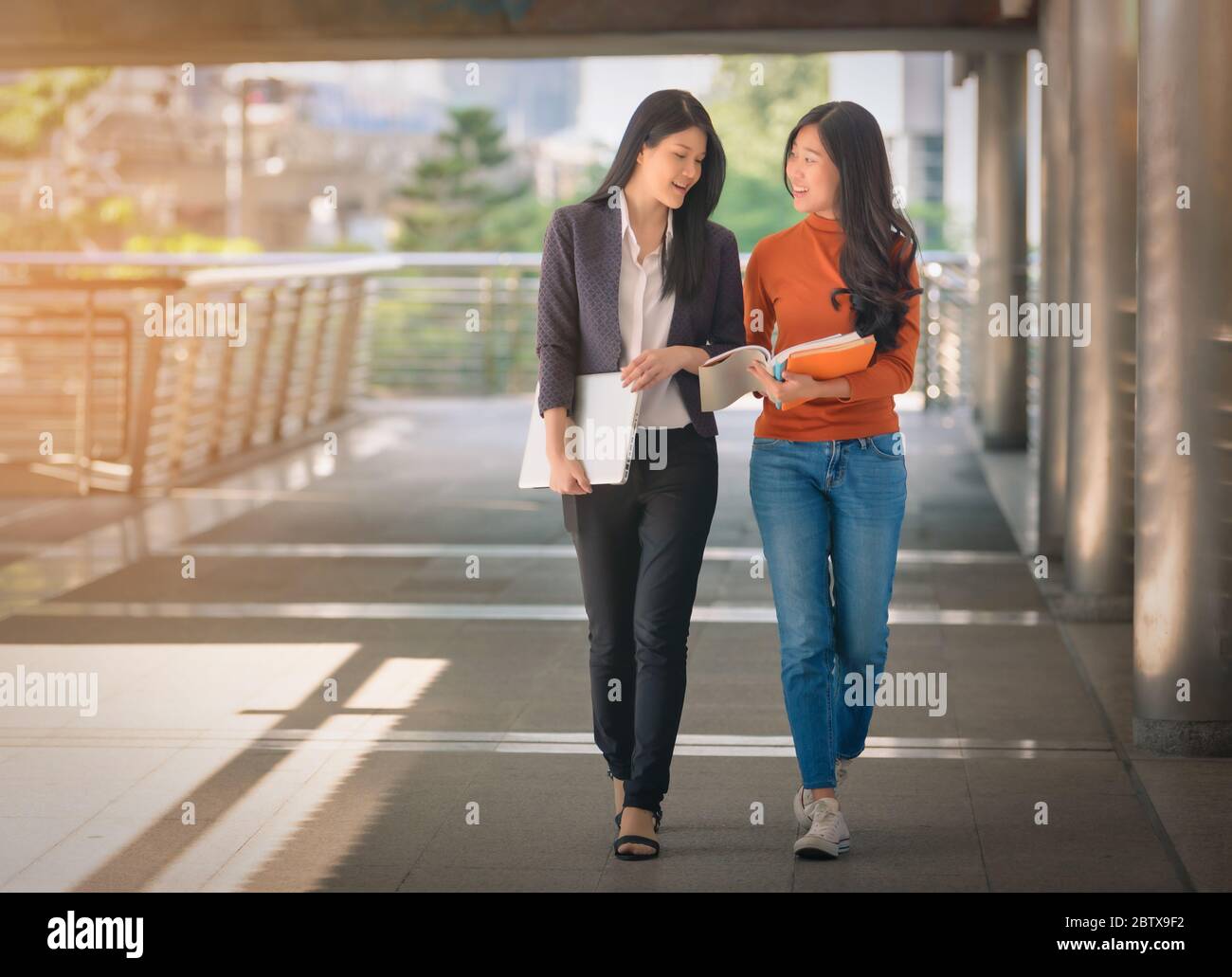 Diversity Teenagers holding laptop computer and reading a book walking ...