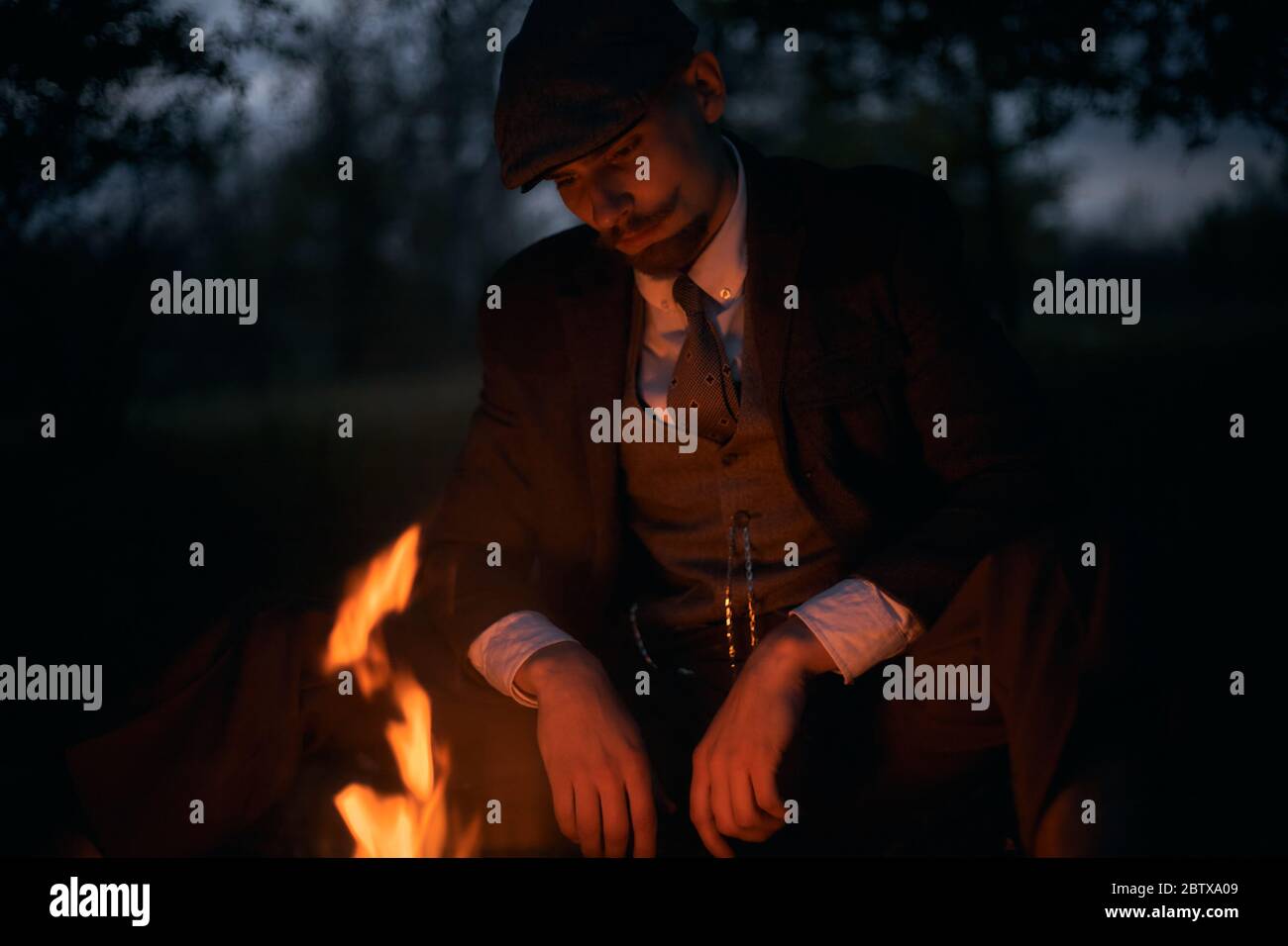 Portrait of a guy sitting by the fire at night in nature. Cinematic ...