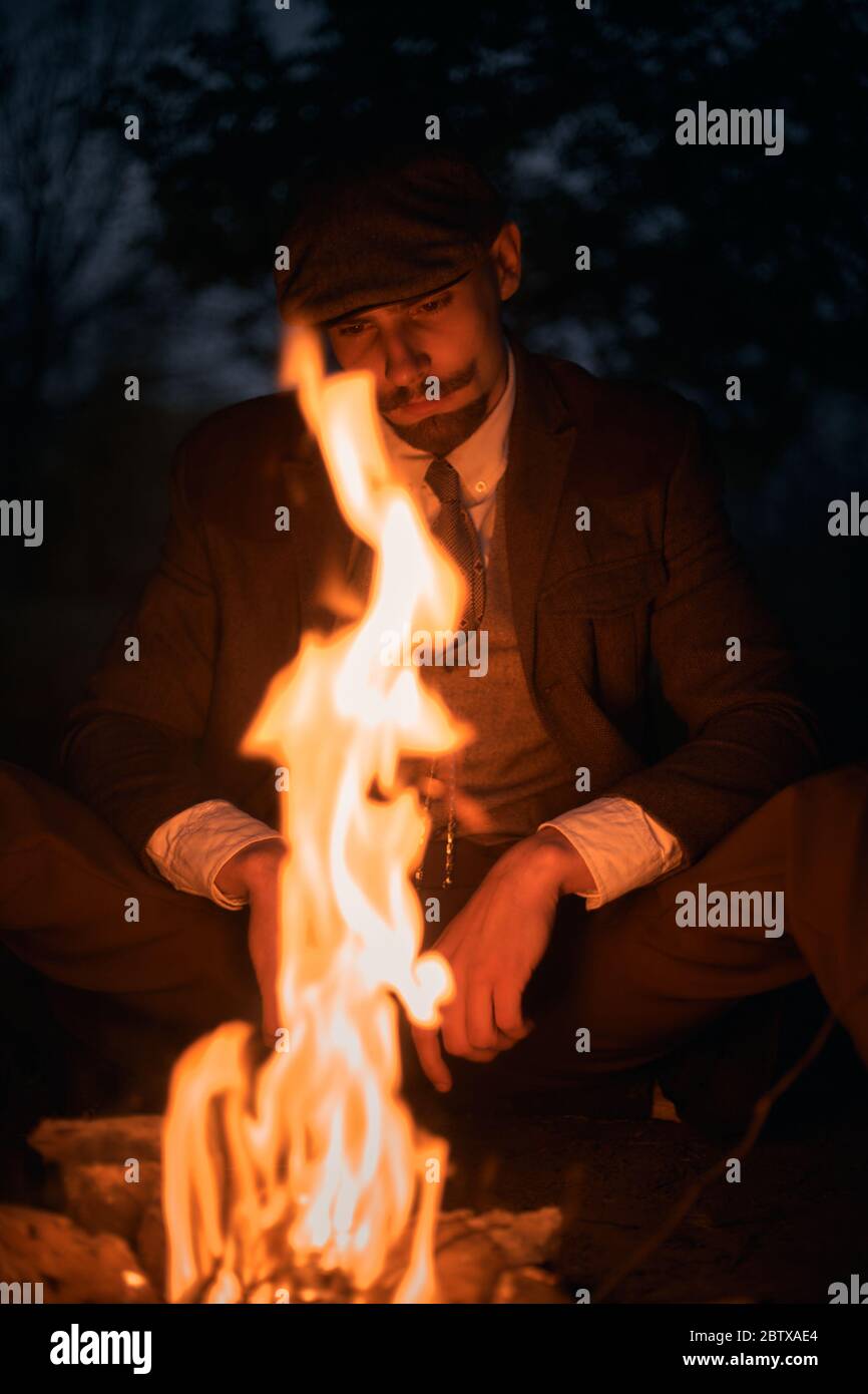 Portrait of a guy sitting by the fire at night in nature. Cinematic ...