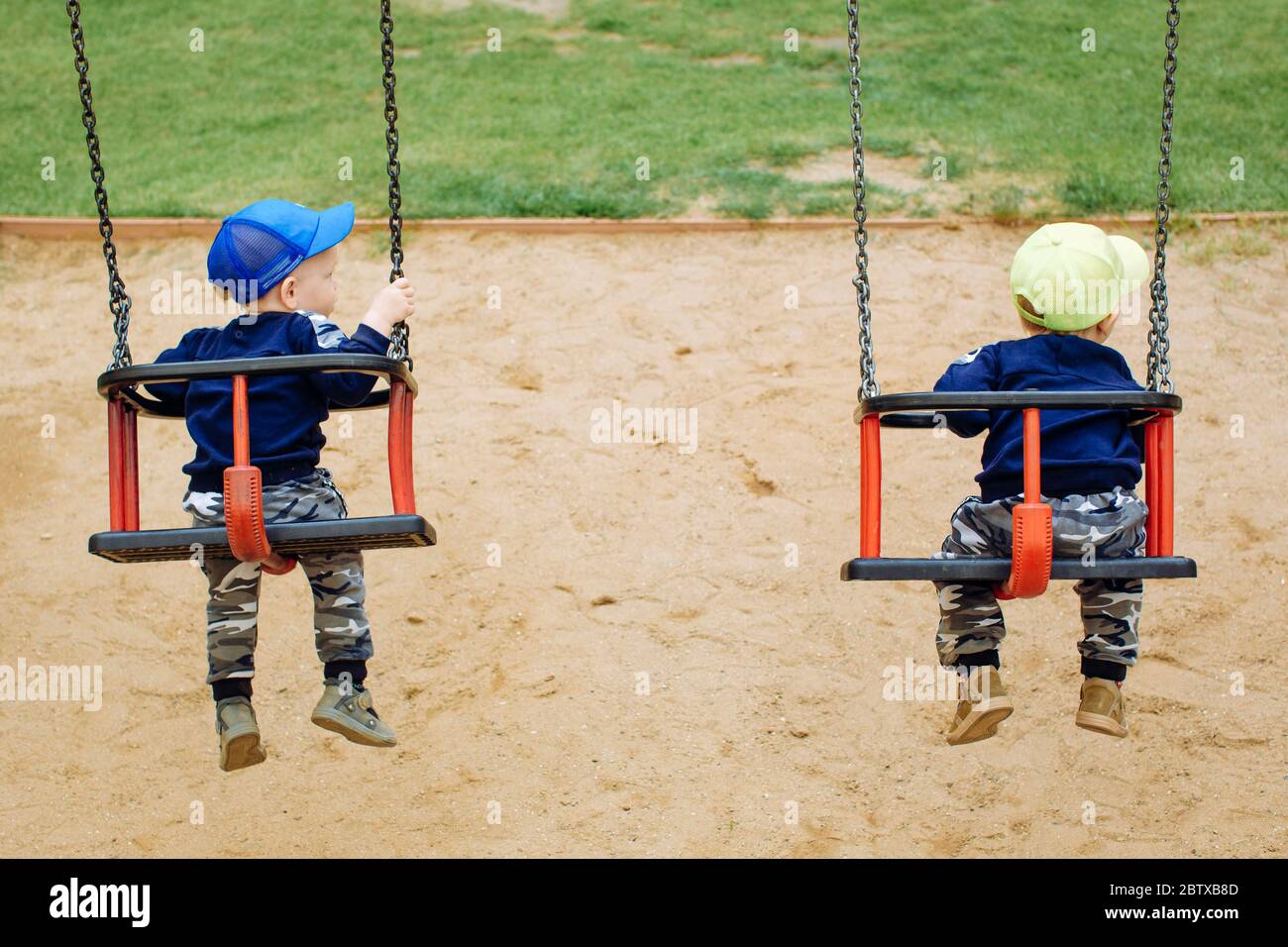 2 twin brothers ride together on a swing, 1-2 years Stock Photo - Alamy