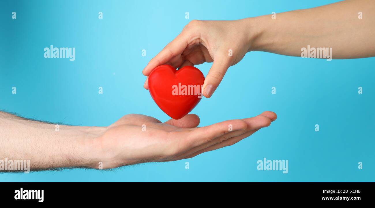 Female hand puts heart on male hand on blue background Stock Photo - Alamy