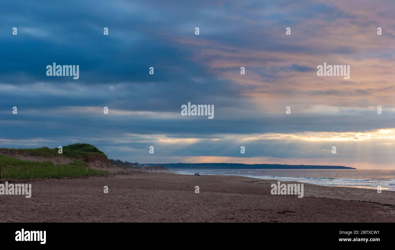 Dramatic sunset at Cavendish Beach, PEI National Park, Canada. Couple ...
