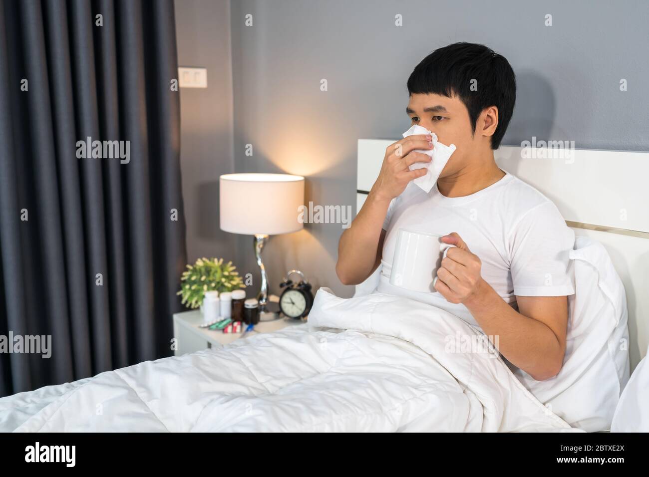 sick man drinking a cup of hot water on a bed Stock Photo - Alamy