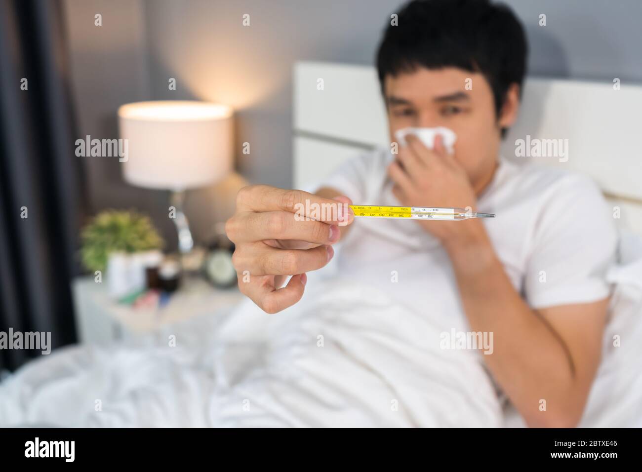 sick man using thermometer and showing high temperature in a bed Stock ...
