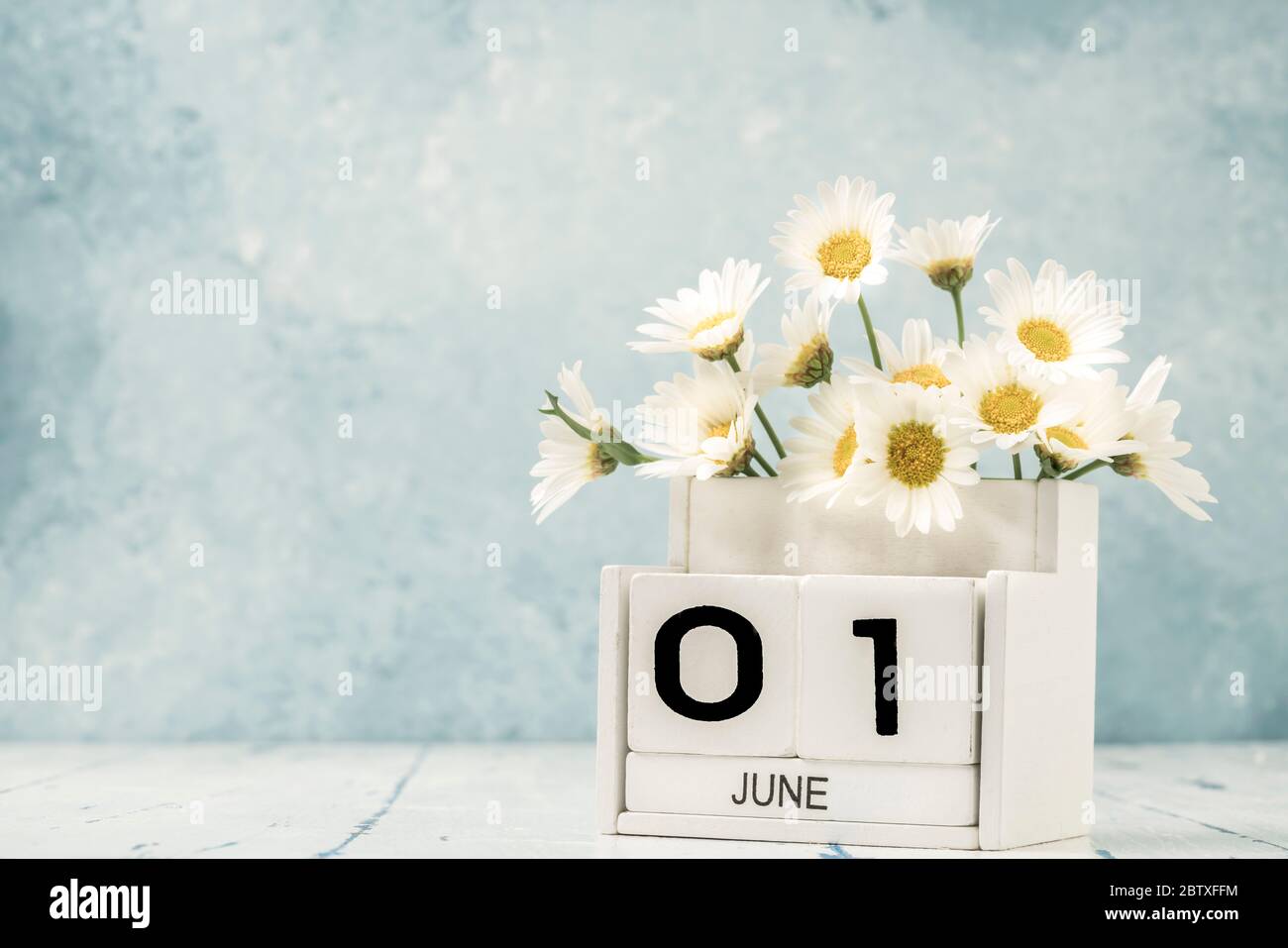 White cube calendar for june decorated with daisy flowers over blue ...