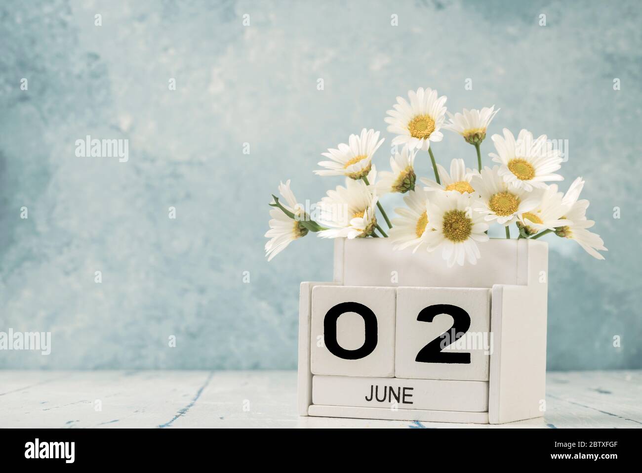 White cube calendar for june decorated with daisy flowers over blue ...