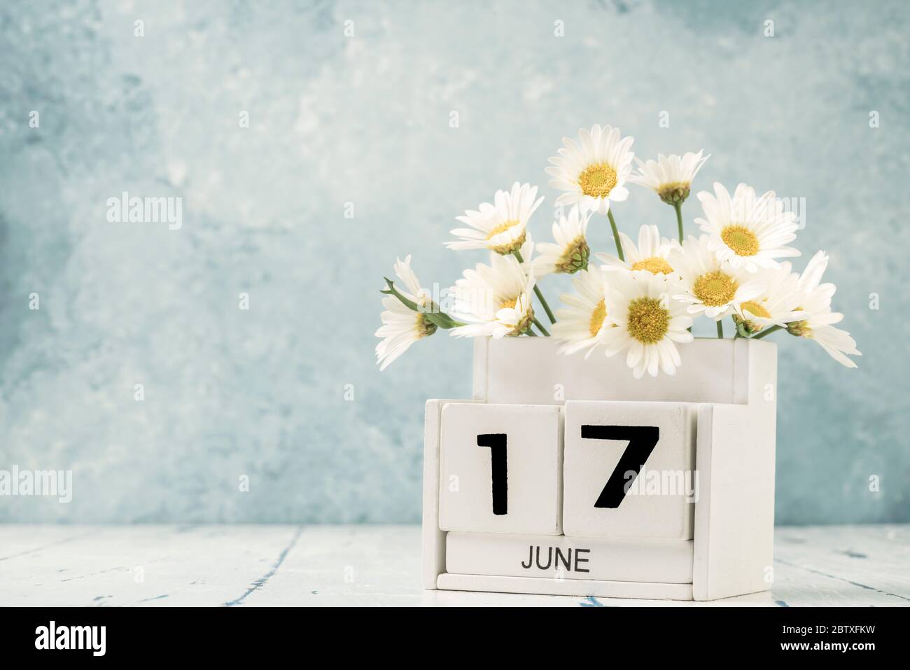 White cube calendar for june decorated with daisy flowers over blue ...
