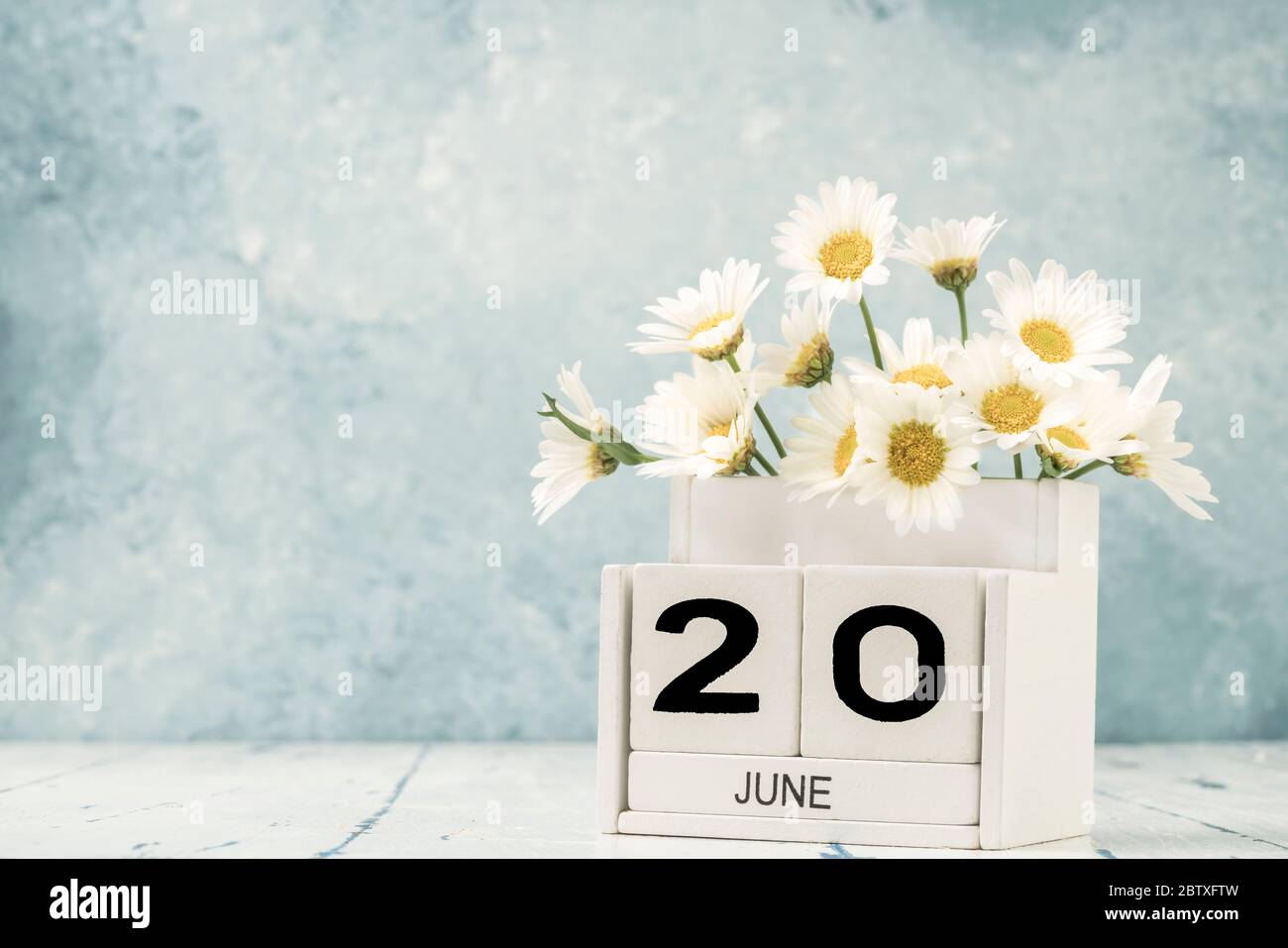 White cube calendar for june decorated with daisy flowers over blue ...