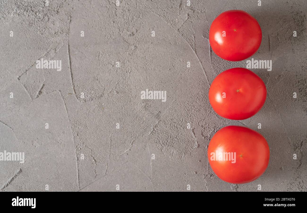 Tomato's line. Three tomatoes. Copy space. Place for message. Concrete ...