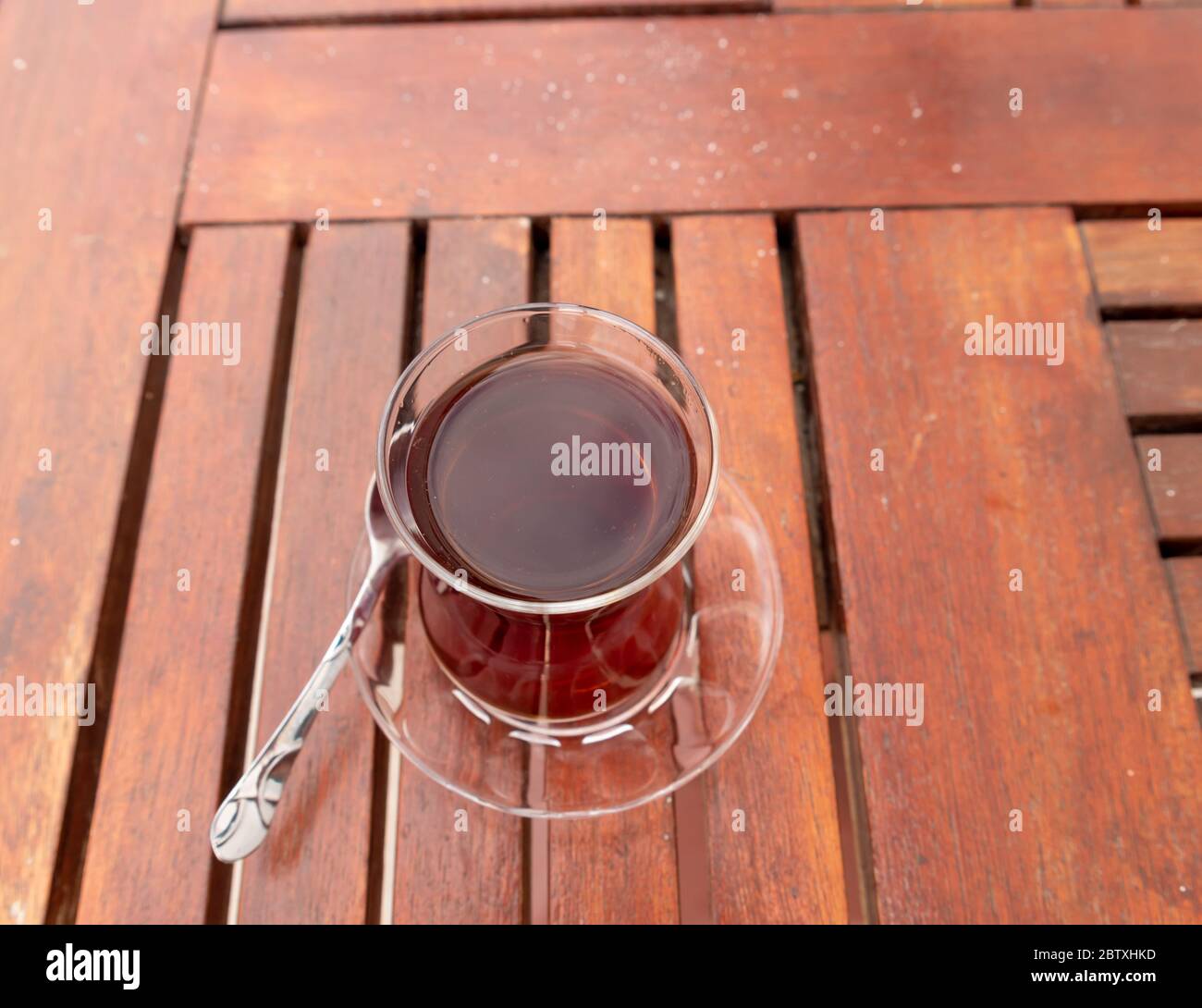 Turkish black tea glass with teaspoon on the wooden table. Turkish ...