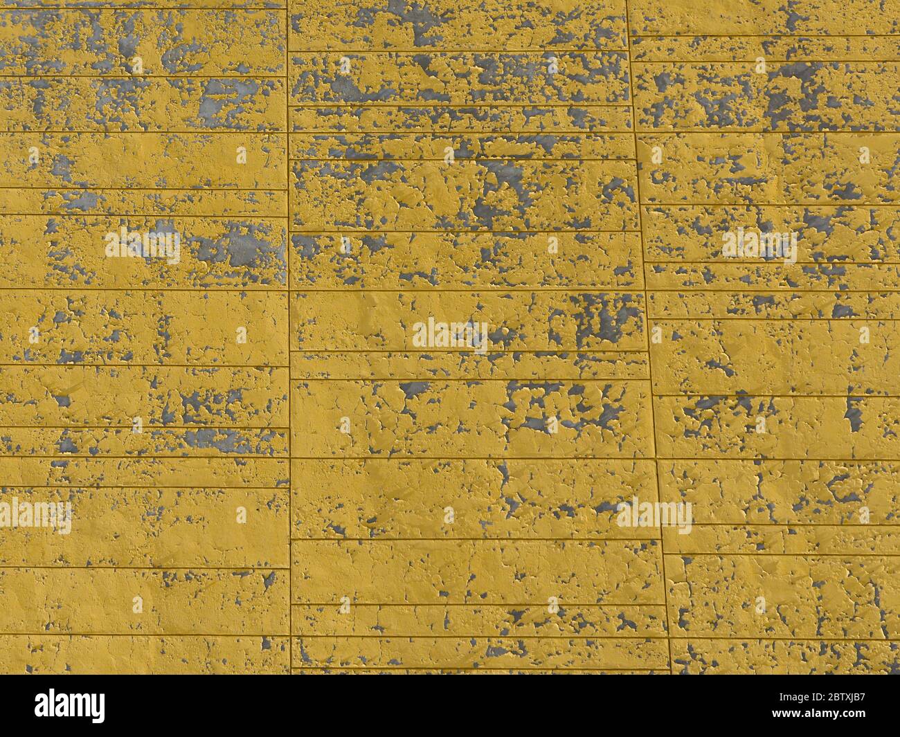 Weathered and scratched yellow paint on a concrete wall. Rough texture ...