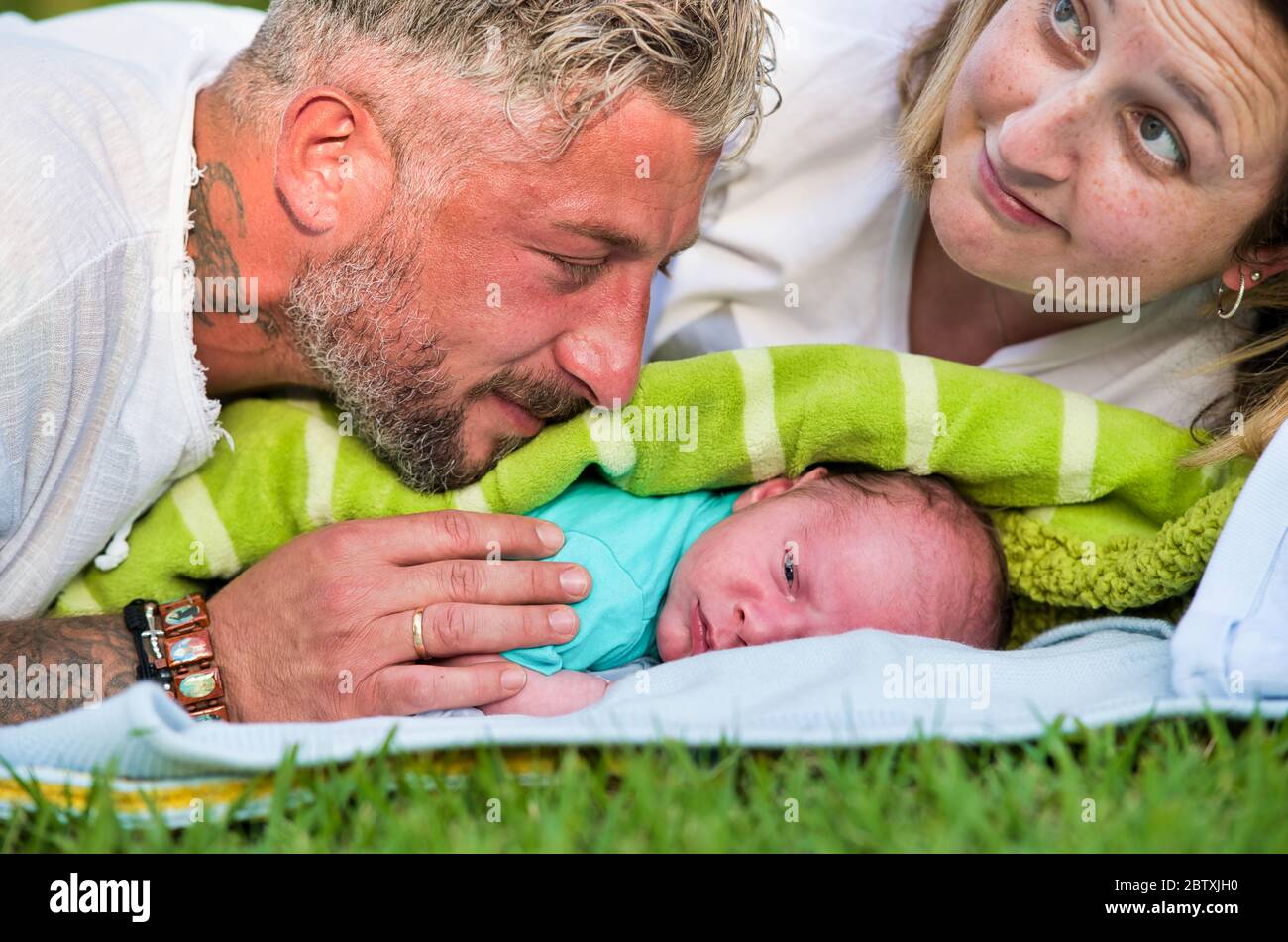 Newborn baby lying down outdoor in the city park with his parents ...
