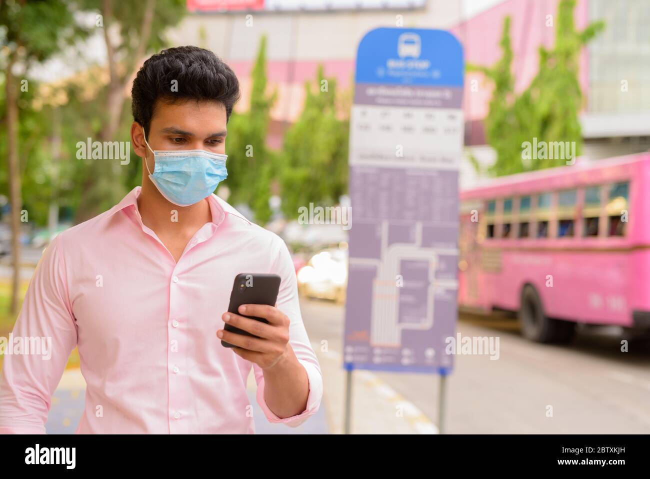 Young man using mobile phone at bus stop hi-res stock photography and ...