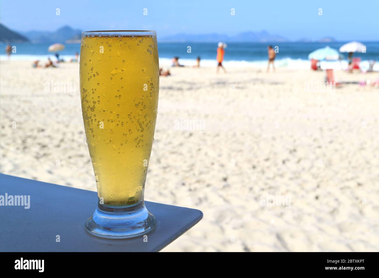 Glass of cold draft beer against sunny Copacabana beach in Rio de ...