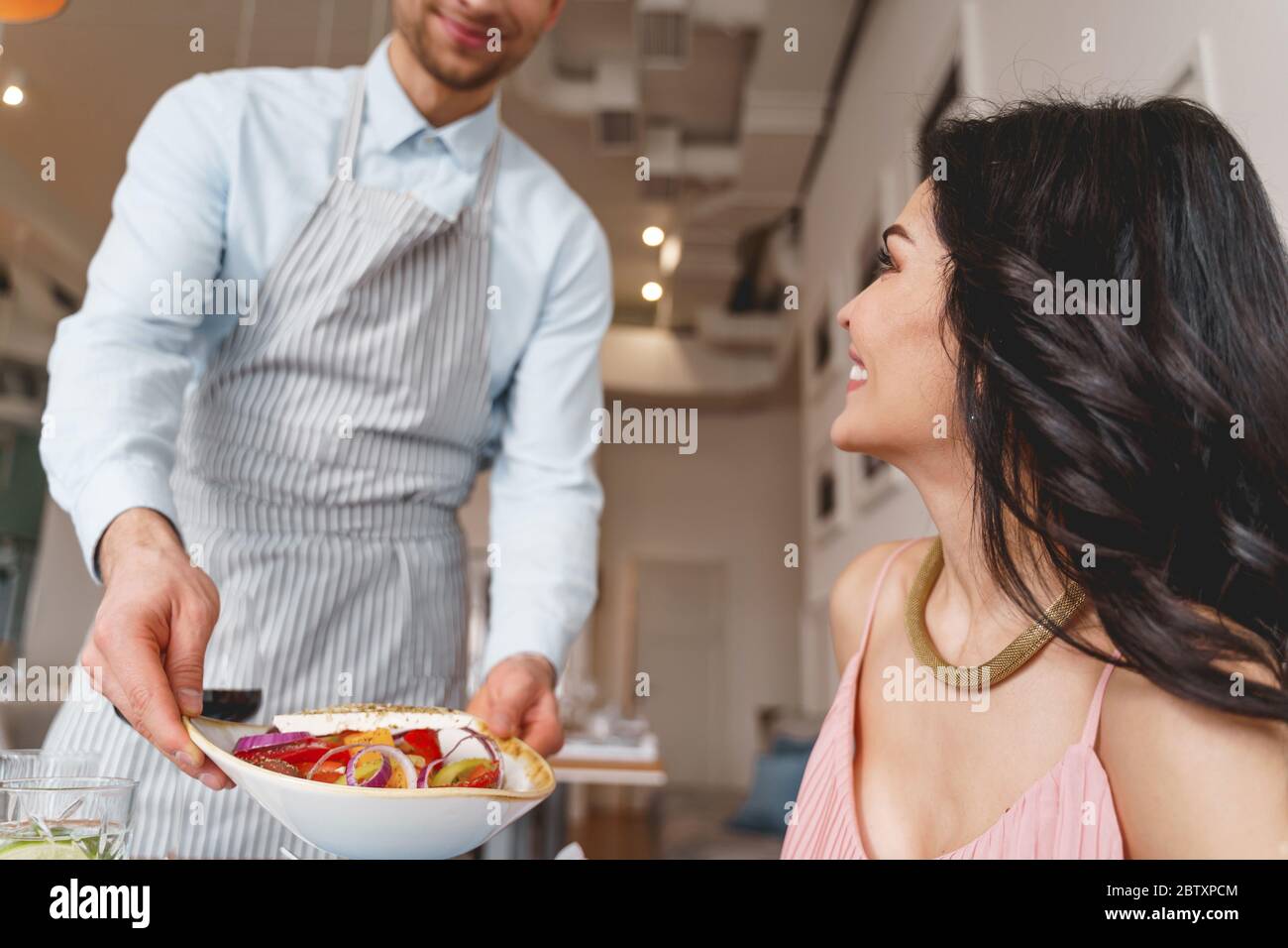 Smiling waiter serving food to charming lady Stock Photo - Alamy