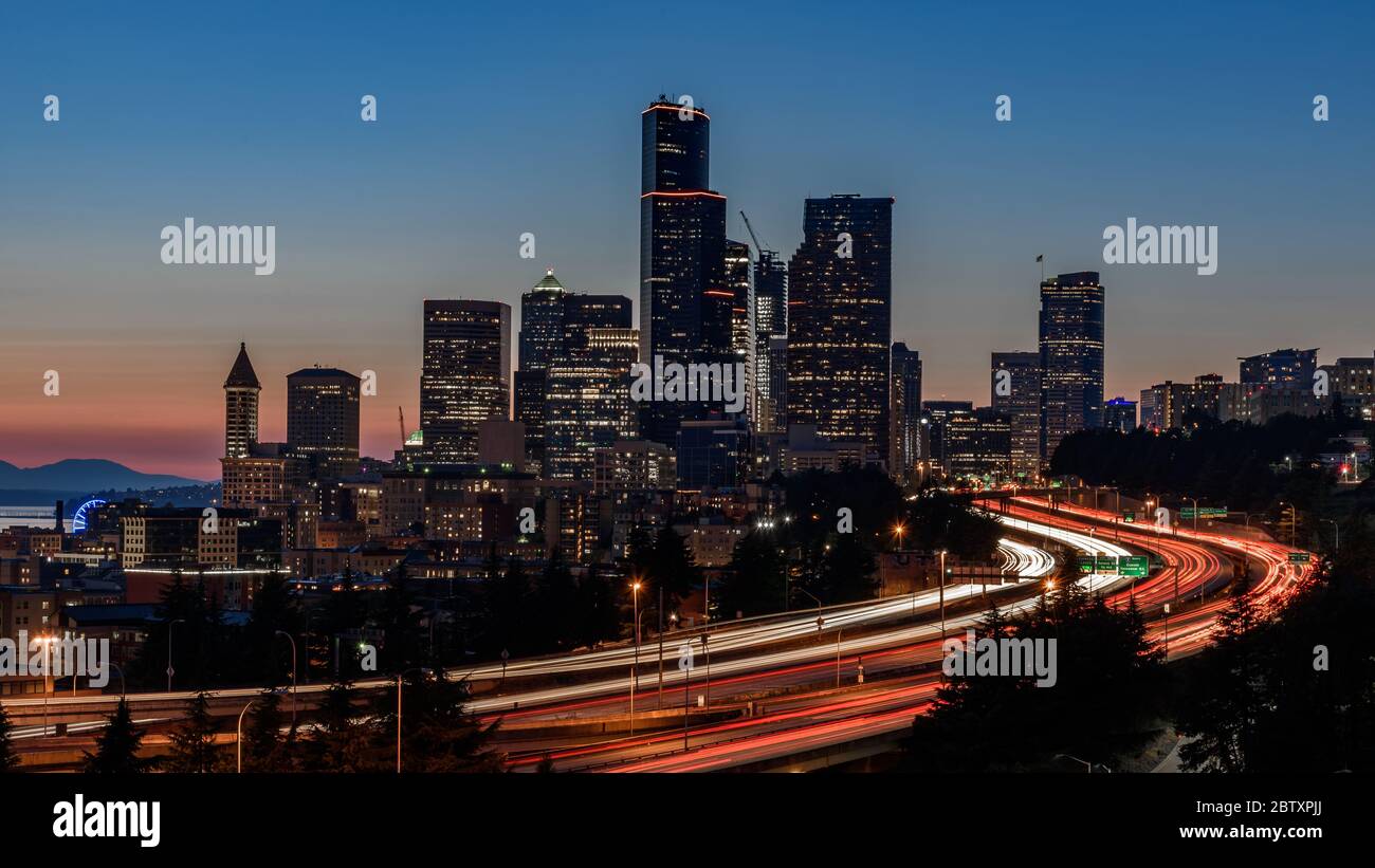 Seattle skyline, at sunset. The cars along the highway are creating ...