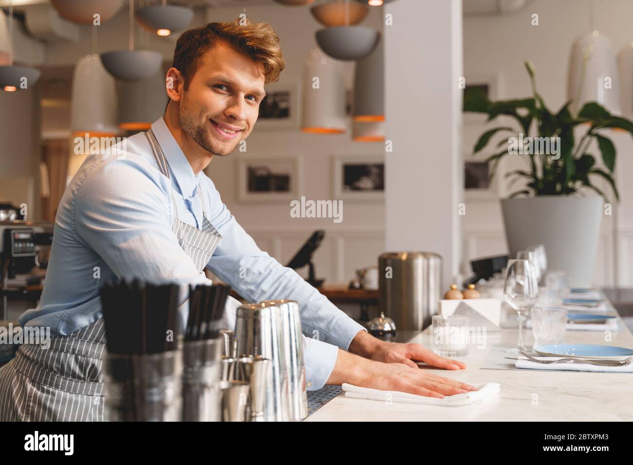 Cheerful bartender standing at the bar counter Stock Photo - Alamy