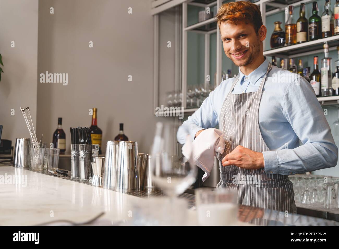 Handsome bartender wiping glass with special rag Stock Photo - Alamy