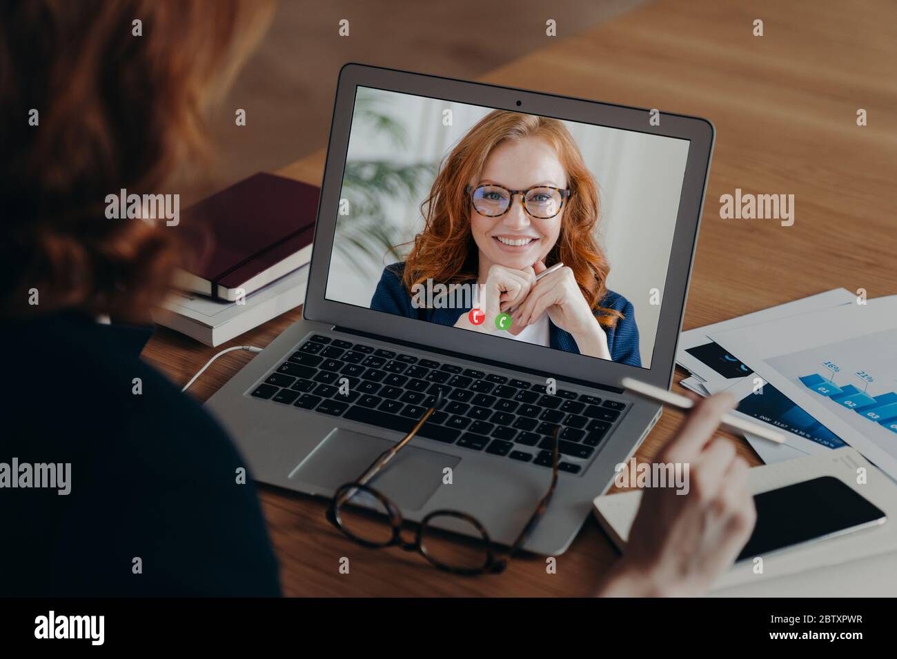 View over shoulder of female freelancer talks with employee by video ...