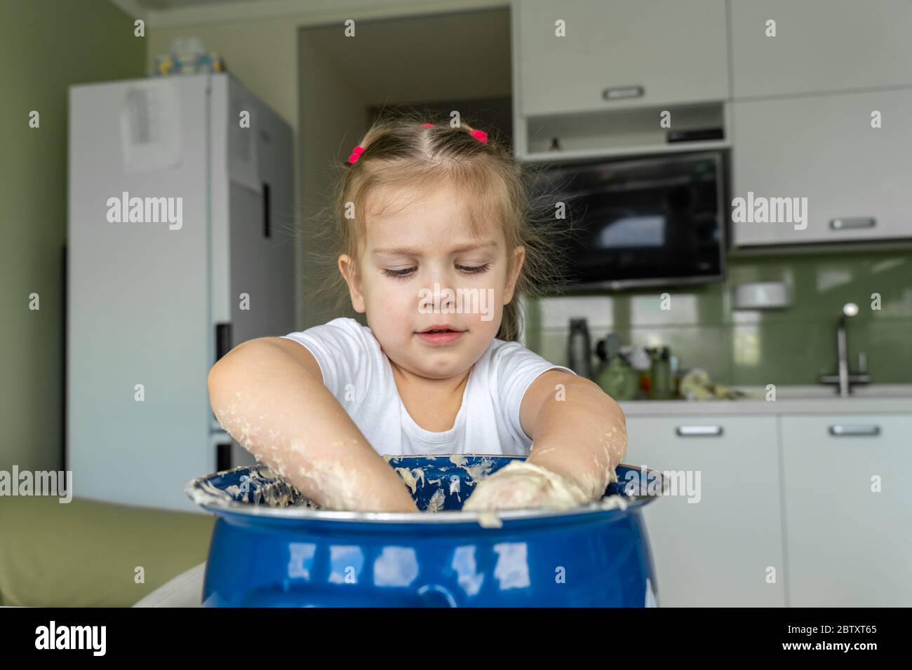 child preschooler plays in the kitchen with dough. girl dropped her ...