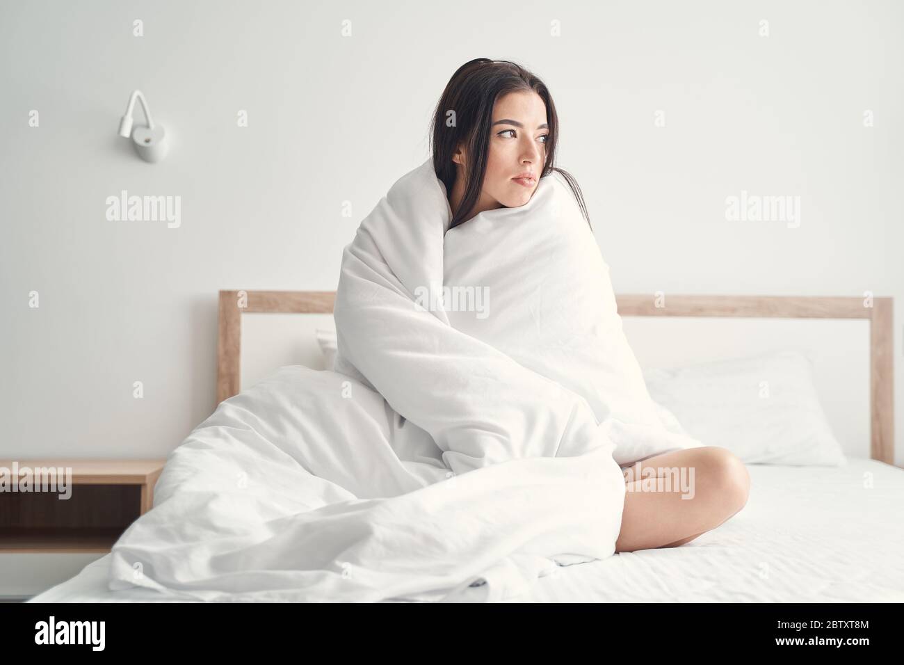Low-spirited dark-haired Caucasian lady sitting in bed Stock Photo - Alamy