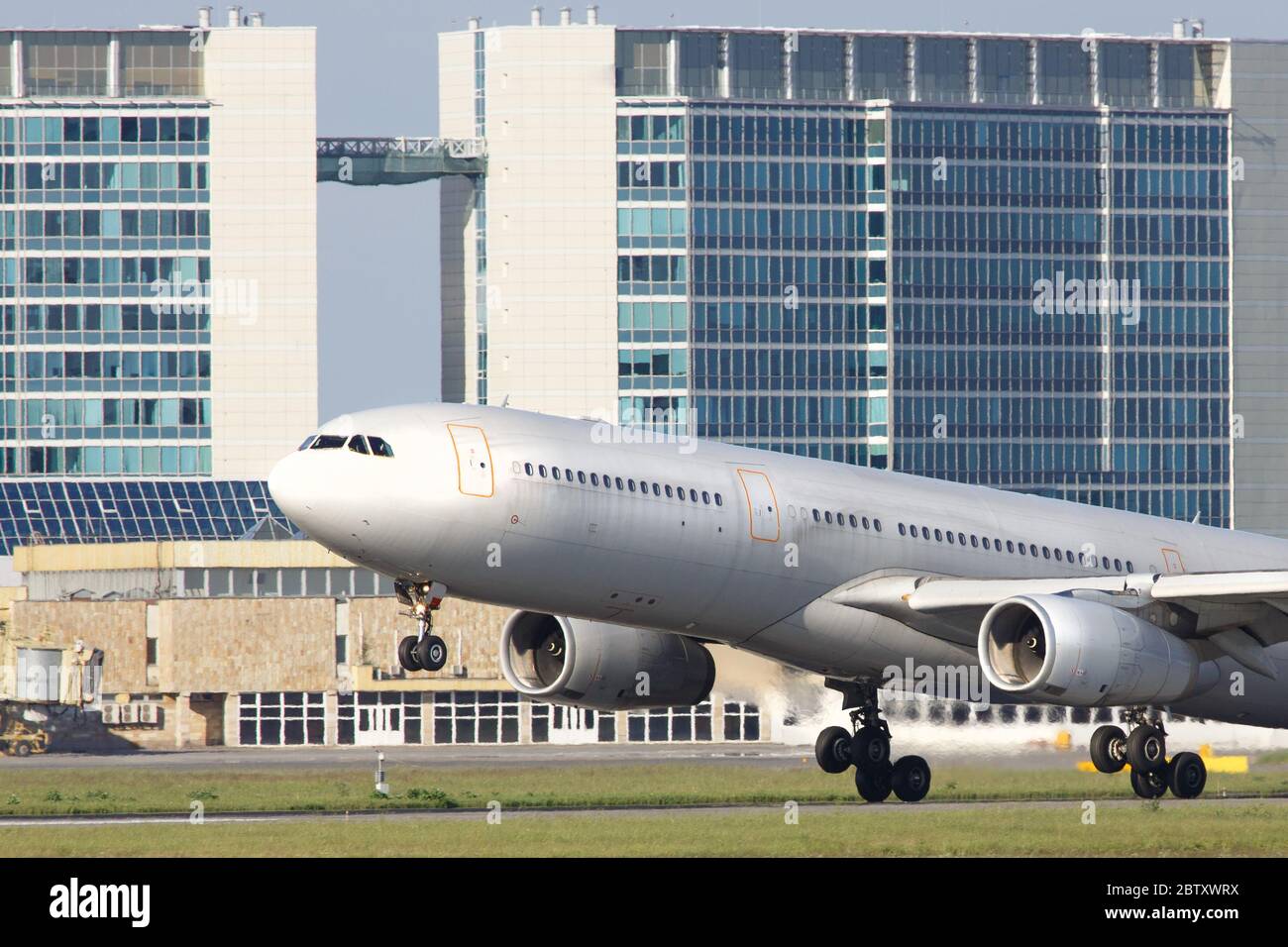 Close up of wide-body modern passenger airplane take off, building on ...