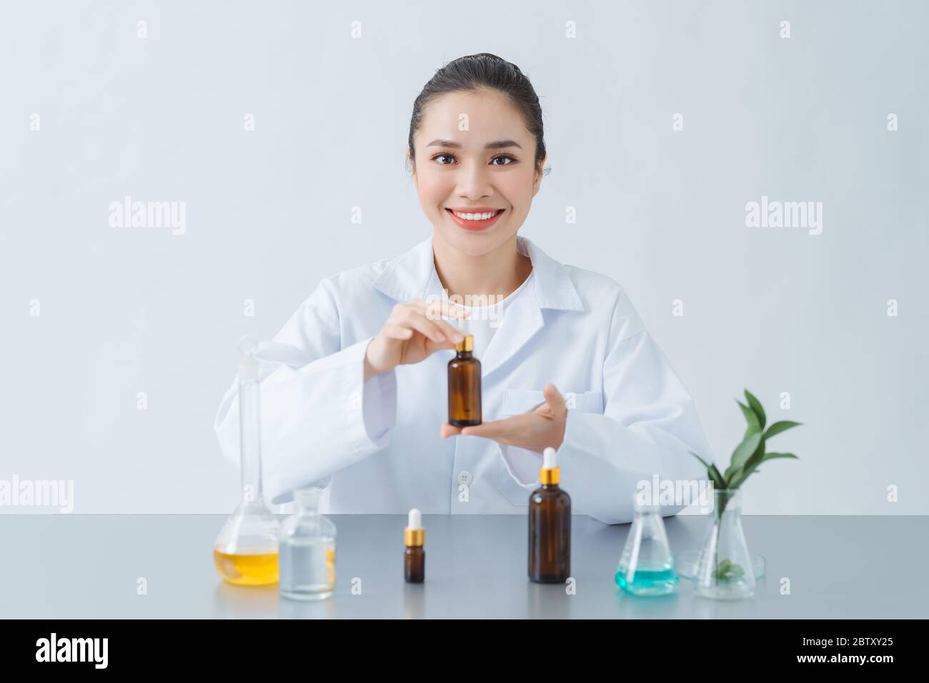 Female dermatologist holding bottle of skin care product over table ...